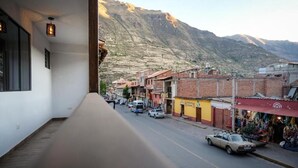 Vista da rua com prédios, uma montanha ao fundo e um carro estacionado na lateral.