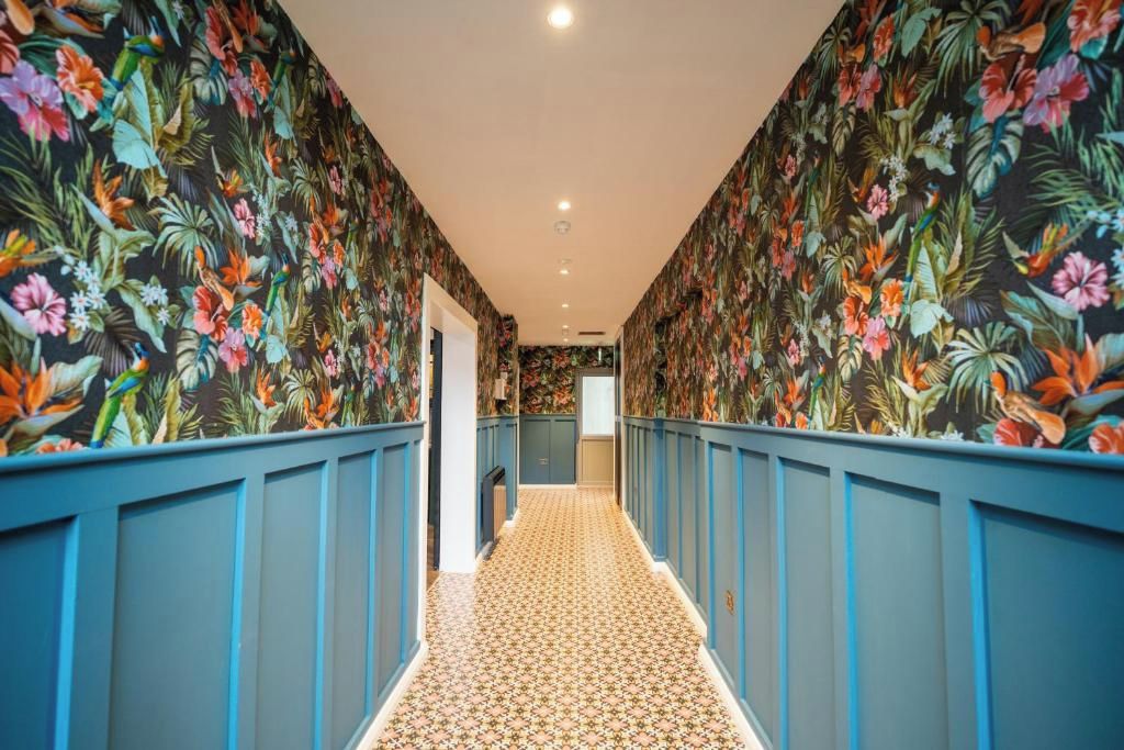 Corredor com papel de parede floral e painel azul.