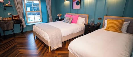Quarto com duas camas, uma escrivaninha e uma janela com cortinas.