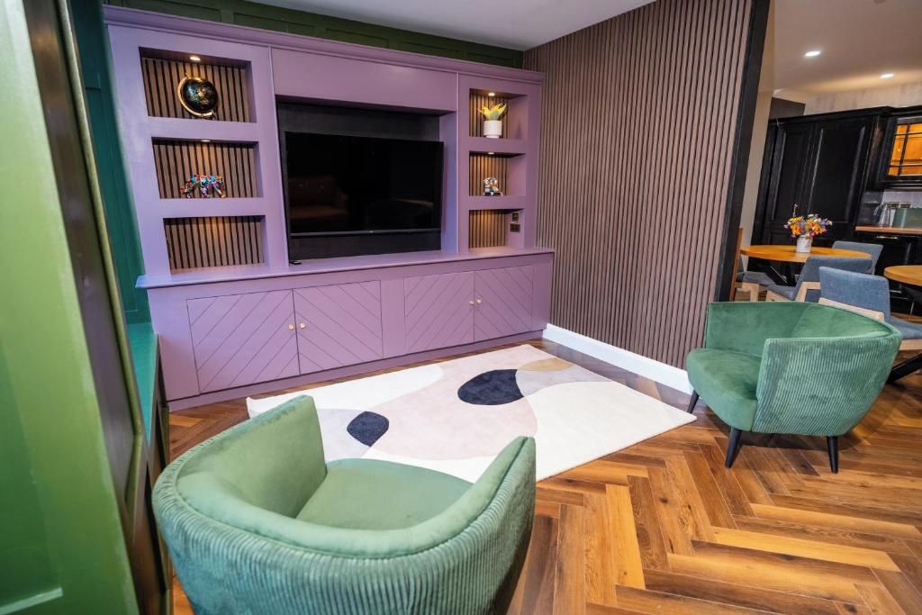 Uma sala de estar moderna com uma grande televisão de tela plana, prateleiras embutidas e piso de madeira em padrão herringbone.
