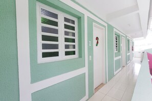 Corredor com paredes verdes, molduras brancas e piso ladrilhado.