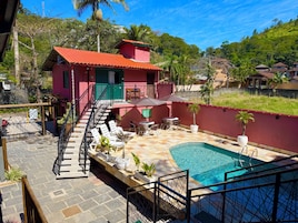 Um edifício de dois andares com telhado vermelho e uma piscina.