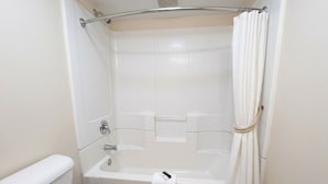 Um banheiro pequeno e branco com banheira, vaso sanitário e porta-toalhas.