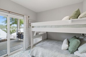 Uma cama de solteiro com vista para uma varanda e uma porta que dá para o exterior.