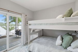 Uma cama de solteiro com vista para uma varanda e uma porta que dá para o exterior.