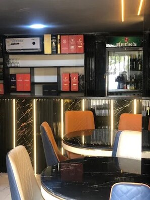 Uma área de bar com bancada preta, caixas vermelhas em prateleiras e um refrigerador Beck's.