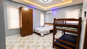 Quarto com cama beliche, cama de solteiro, guarda-roupa e ar condicionado.
