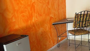 Quarto com frigorífico, uma cadeira e chão em azulejos.