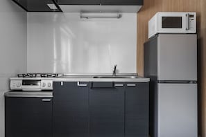 Uma cozinha moderna com fogão a gás, micro-ondas e frigorífico.