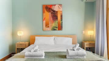Quarto de hotel com cama, duas mesas de cabeceira, um quadro na parede e uma janela com cortinas.