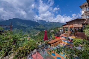 Restaurante com área externa e mesas apreciando uma paisagem montanhosa.