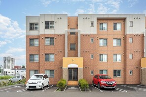 Um edifício de apartamentos com vários andares e um estacionamento em frente.