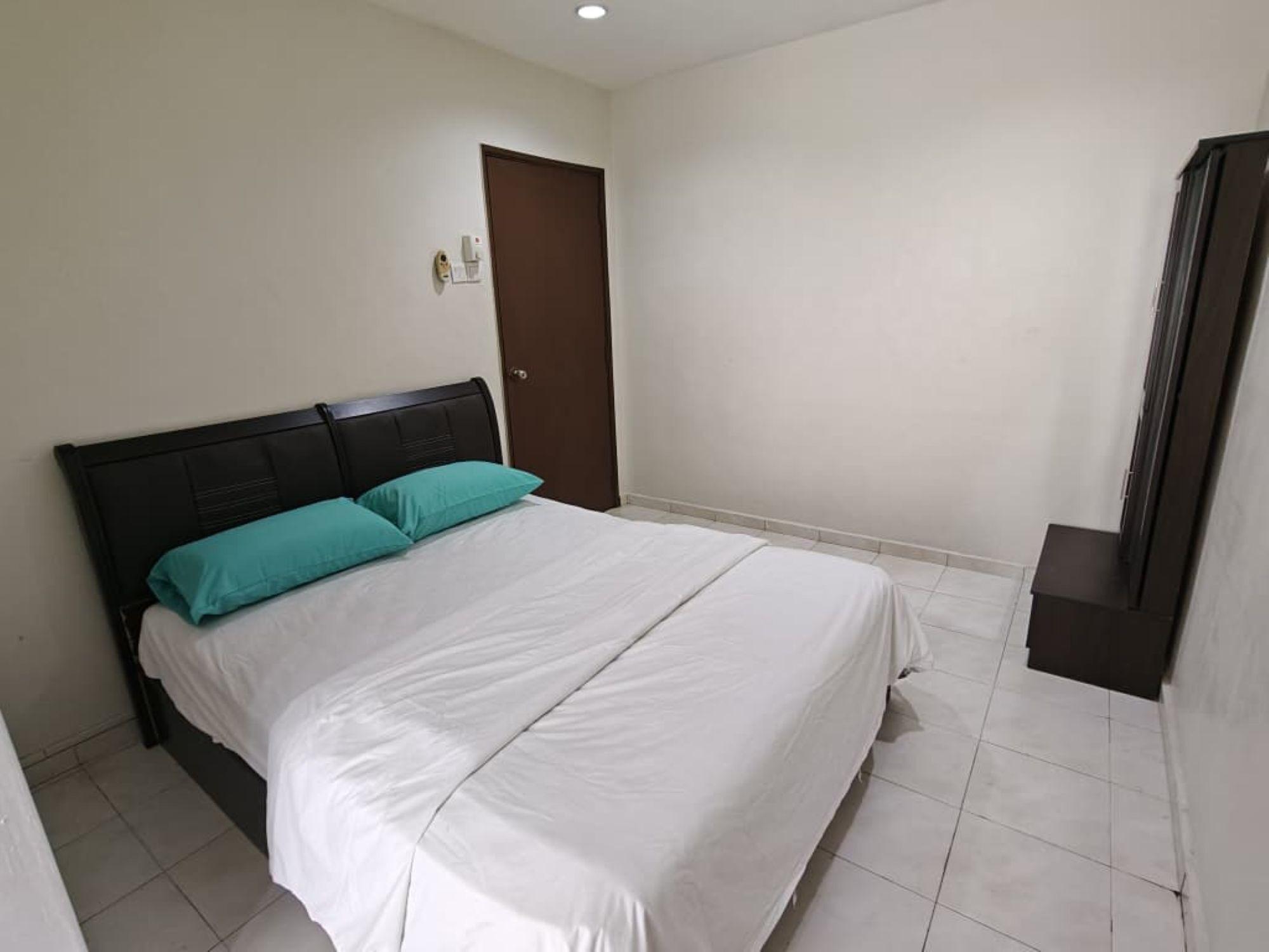 Quarto com cama, porta e uma pequena janela.