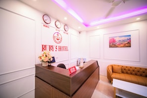 Uma receção de hotel com relógios, um logótipo e um quadro na parede.