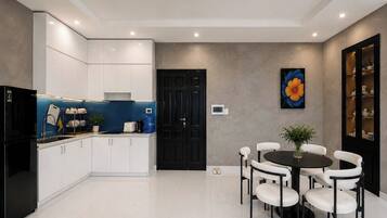 Cozinha moderna com armários brancos, geladeira preta e painel de parede azul.