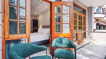Quarto de hotel com cama, escrivaninha e uma janela grande.
