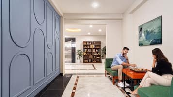 Uma sala de estar moderna com uma mesa de xadrez, um sofá verde e uma estante.