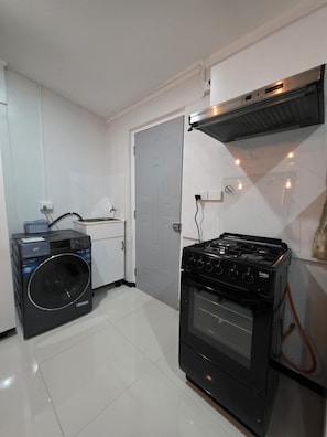 Uma cozinha compacta com máquina de lavar, fogão e bancada pequena.