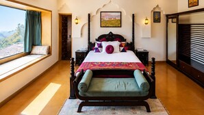 Quarto com cama grande, janela com cortinas, ventilador de teto e um quadro na parede.