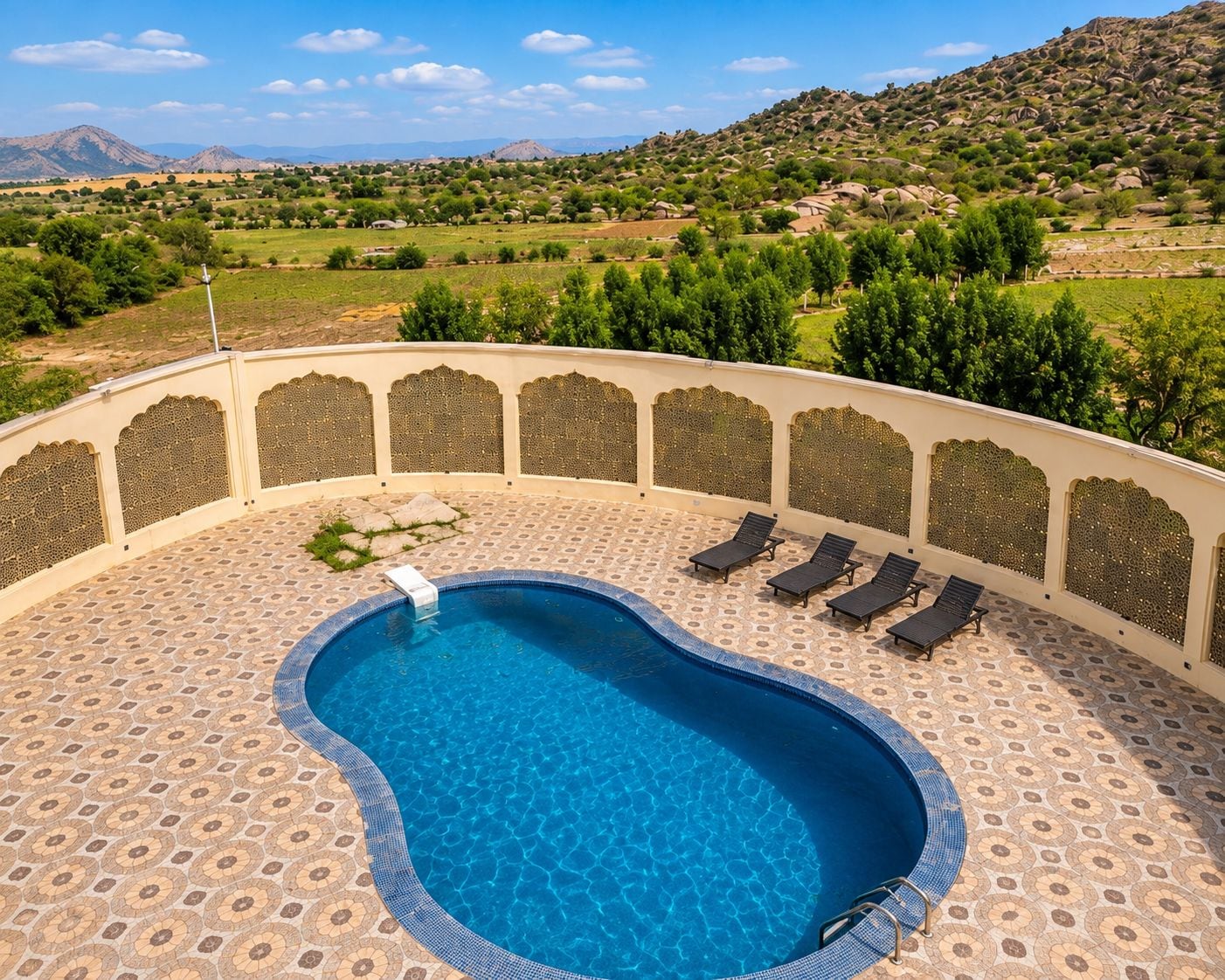 Piscina com borda em azulejo, cercada por piso estampado, e vista para paisagem montanhosa.