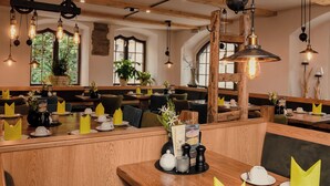 Interior de restaurante com bancos de madeira, luminárias pendentes e uma estrutura central em madeira.
