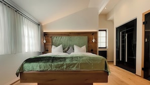 Quarto moderno com cama grande, cabeceira de madeira e vista para um armário.