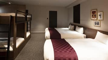 Quarto de hotel com beliches, uma cama grande e manta xadrez.