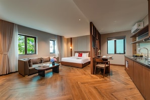 Quarto de hotel moderno com sofá, cama, área de refeições e cozinha.