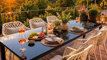 Mesa de jantar posta com cadeiras, um copo de vinho e uma cesta de frutas.