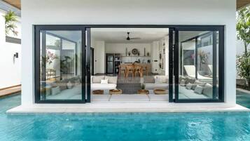 Uma casa moderna com piscina, sala de jantar e sala de estar com sofás e uma mesa de centro.