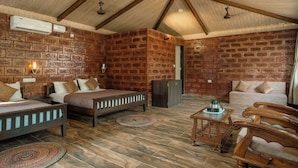Quarto com parede de tijolos, uma cama, um sofá, mesa de madeira e ventoinha no teto.