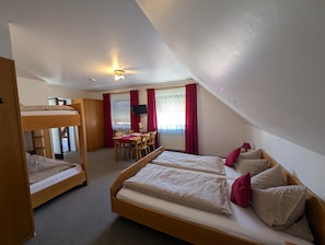 Quarto estilo dormitório com beliches, escrivaninha e televisão.
