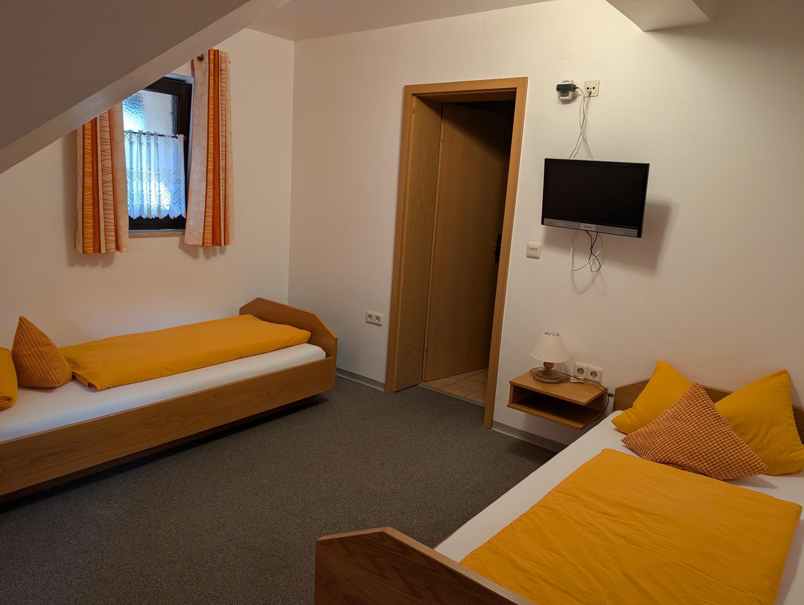 Quarto com cama, televisão, mesa de cabeceira e janela com cortinas.