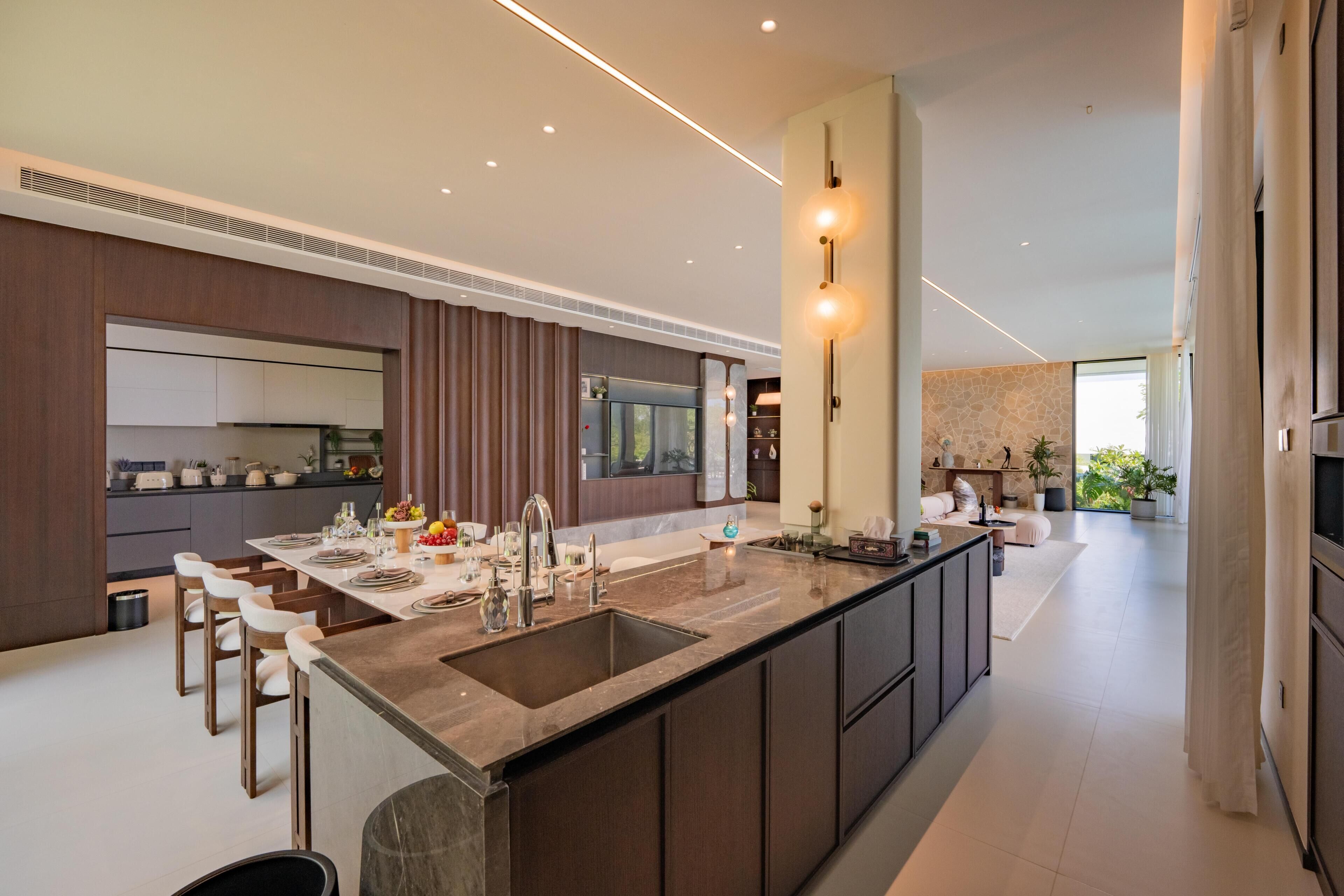 Cozinha moderna com uma ilha grande, eletrodomésticos embutidos e área de refeições com banquetas.