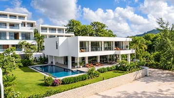 Uma casa moderna de dois andares com piscina, área de estar externa e vegetação exuberante.