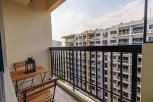 Varanda com um banco de madeira e um candeeiro, com vista para um prédio residencial com varandas.