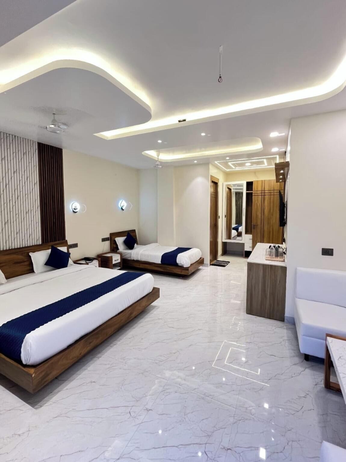 Quarto de hotel moderno com duas camas, um espaço de estar, toucador e banheiro.