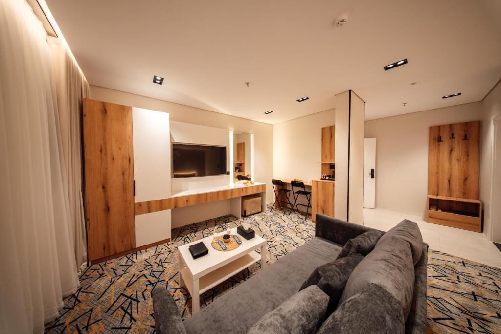 Uma sala de estar moderna com um sofá, uma mesa de centro e uma TV fixada na parede.