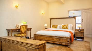 Quarto com cama de dossel, mobiliário de madeira e arandelas.