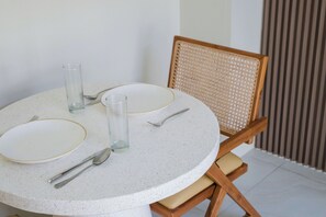 Mesa redonda de jantar com dois pratos, dois copos e talheres.