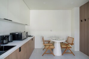 Cozinha moderna com área de jantar, destacando uma mesa redonda e cadeiras de madeira.