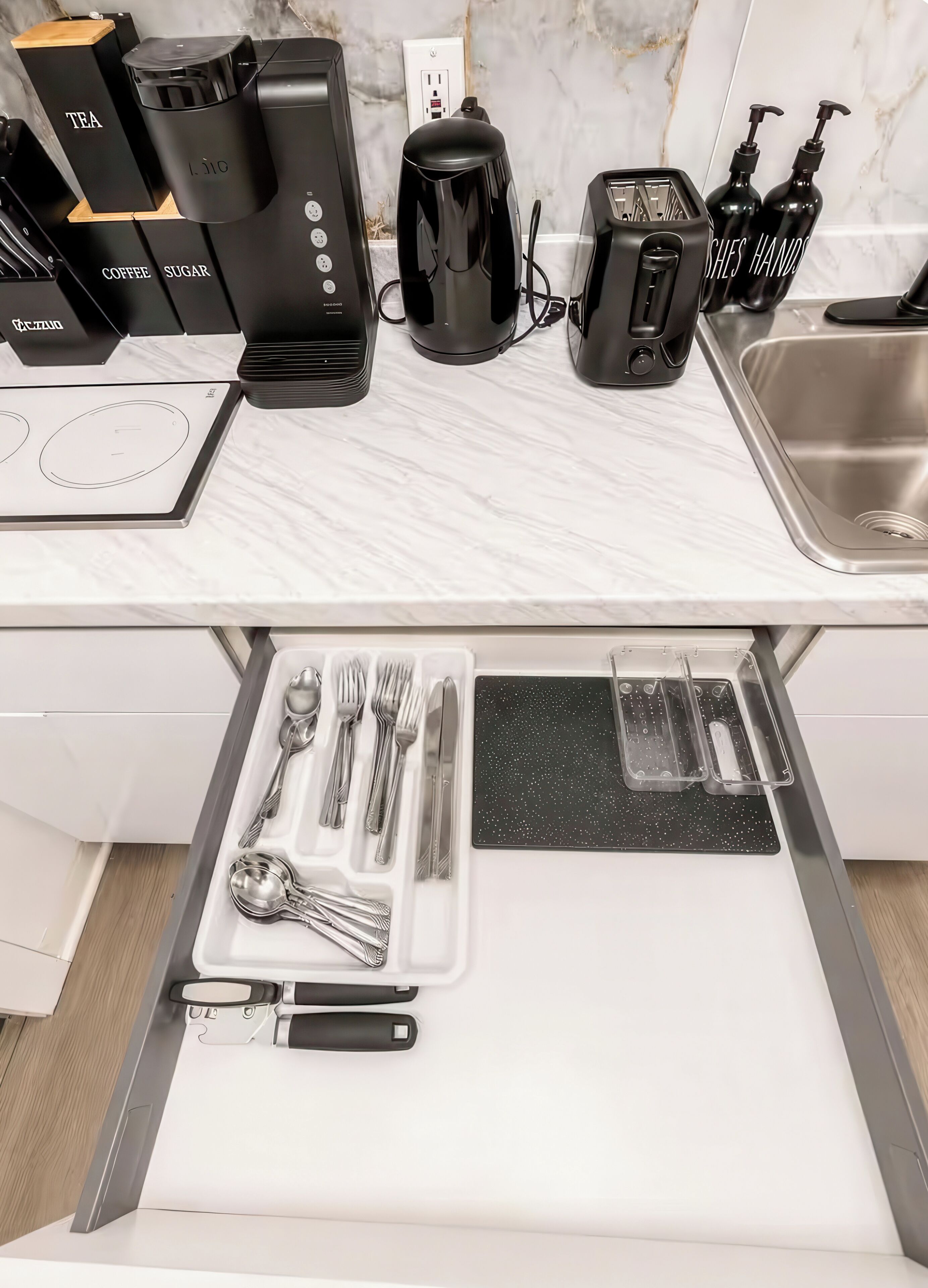 Cozinha moderna com fogão de indução embutido, cafeteira, chaleira e torradeira.