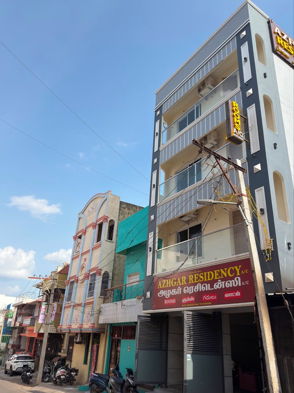 Um edifício de vários andares com uma placa indicando 'AZZHGAR RESIDENCY', mostrando que oferece quartos.