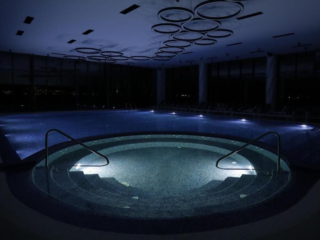 Piscina interna com design circular, em um ambiente escuro.