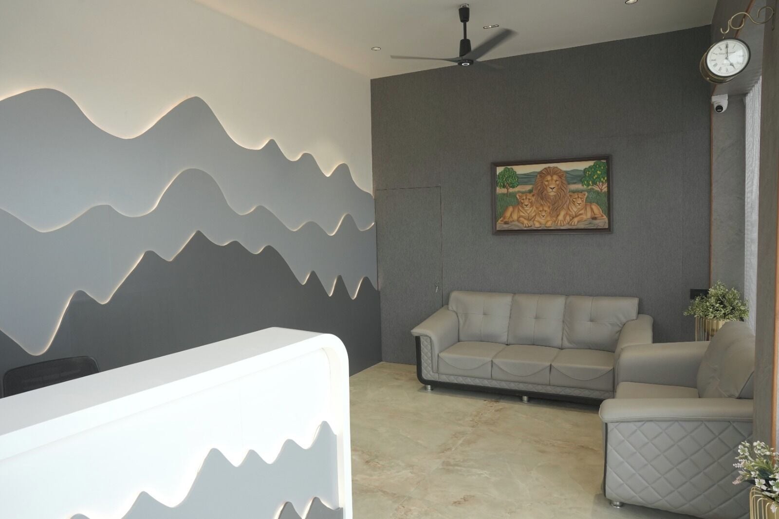 Uma sala de estar moderna com um sofá cinzento, uma unidade de entretenimento branca e um ventilador de teto.