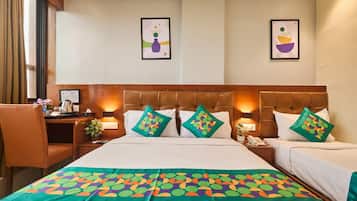 Quarto de hotel com cama grande, duas mesas de cabeceira, escrivaninha e uma cadeira. Há duas imagens emolduradas na parede.