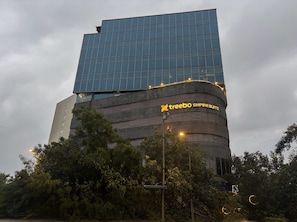 Um edifício moderno com fachada de vidro e uma placa com a inscrição 'Treebo Empire Suite'.