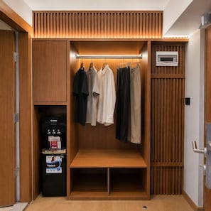 Um closet espaçoso com painéis de madeira, máquina de café embutida e um banco.