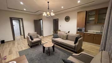 Uma sala de estar moderna com sofá, poltronas, mesa de centro e área de jantar com mesa e cadeiras.