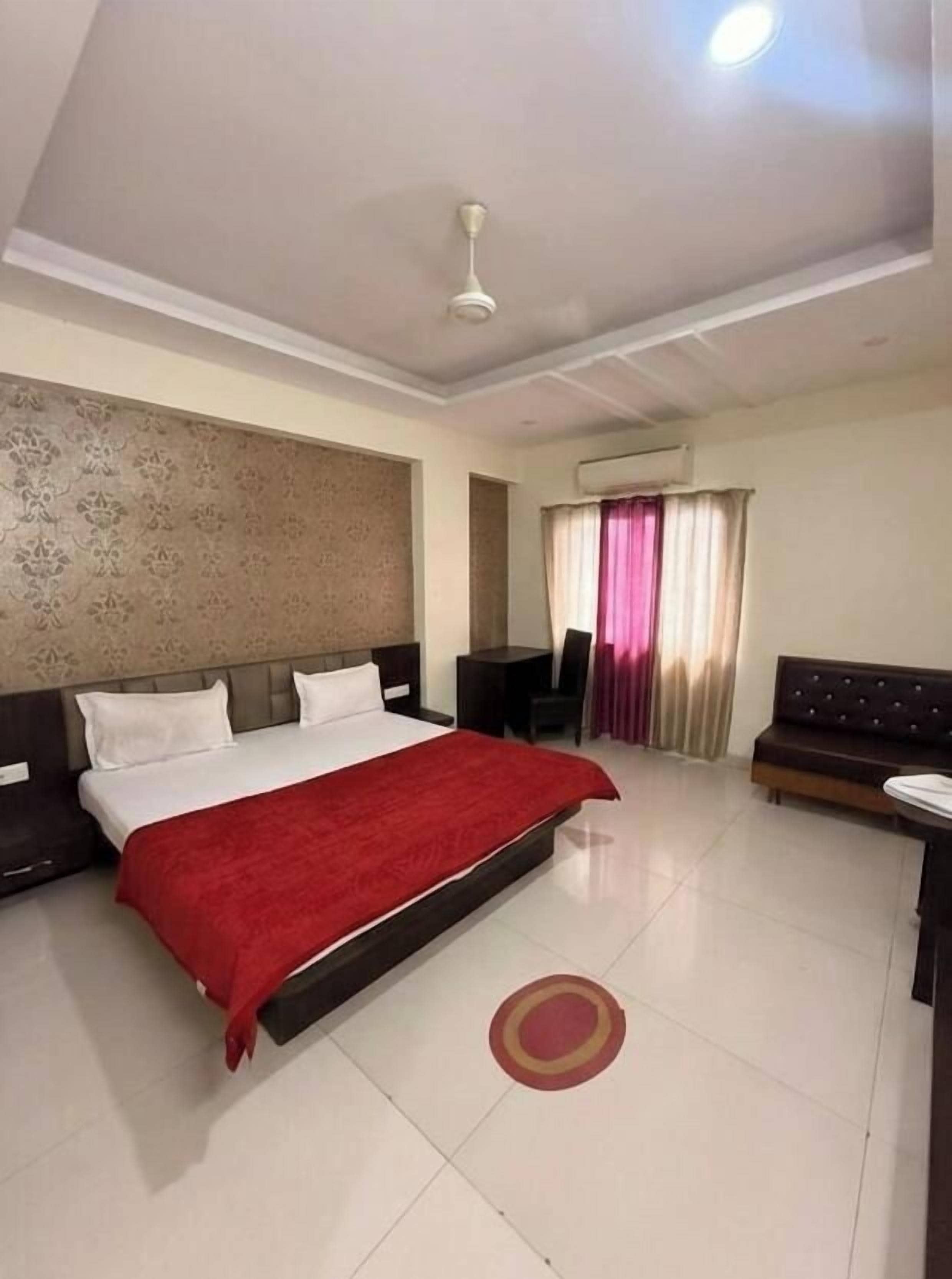 Quarto de hotel com cama, escrivaninha, poltrona, sofá e ar condicionado.